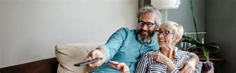 Couple Cuddling On A Couch With A Tv Remote Streaming Their Favorite Series Over Fast Fiber