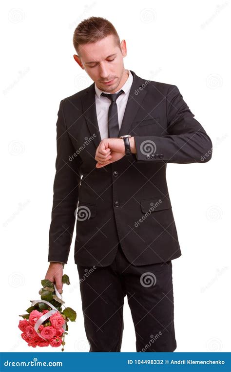 Парень смотрит часы и держит букет на предпосылке изолированной белизной Стоковое Фото