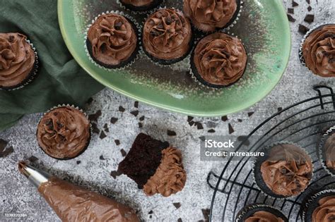 냉각 랙과 녹색 접시의 이미지 종이 케이크 케이스초콜릿 컵 케이크 초콜릿 버터 착빙 파이프 소용돌이 초콜릿 조각 흰색 배경 케이크 파이핑 가방 녹색 모슬린 높은 전망 컵