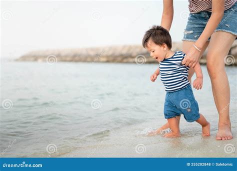 Baby Babe Making His First Steps On The Beach With His Mother Stock