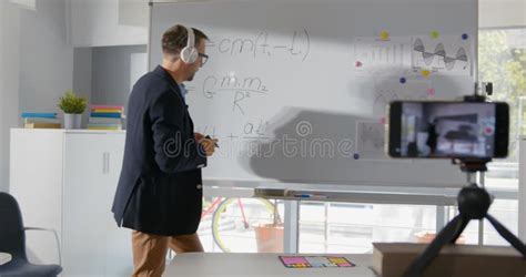 Senior Positive Online Physics Teacher Writing On Board With Formulas Having Online Class Stock