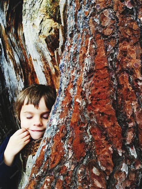 Premium Photo Cute Boy Leaning On Tree Trunk