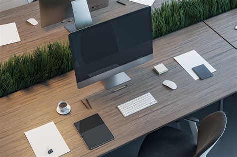 어두운 나무 테이블에 현대 컴퓨터 빈 어두운 화면 디지털 태블릿 커피 컵 및 기타 도구와 녹색 잔디의 파티션으로 분리 된 공동 작업 사무실의 작업 공간 3d 렌더링 모형 0