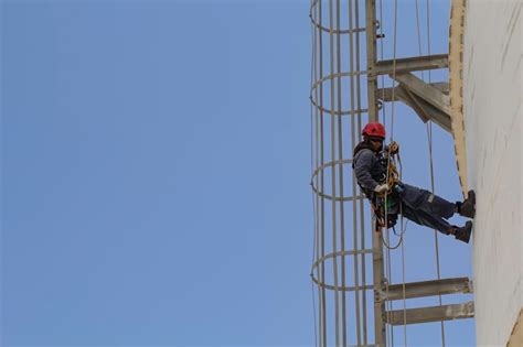 남성 작업자 로프 접근 높이 안전 점검 두께 저장 오일 및 가스 탱크 프리미엄 사진