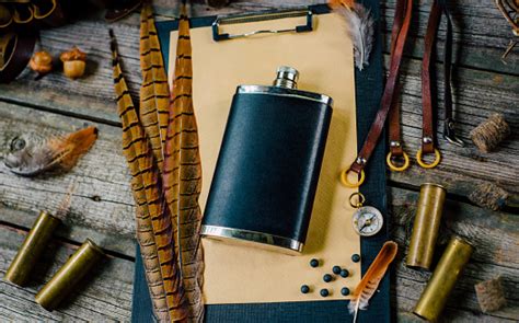 클립 보드와 나무 배경에 그것에 페 전트 깃털에 근접 촬영 플라스 크 빈티지 책상에 사냥 장비 카트리지와 도구가 있는 사냥 용