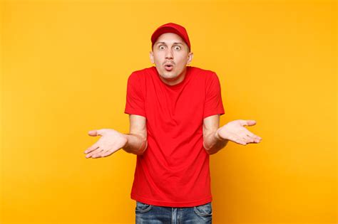 배달 빨간 유니폼에 고립 된 노란색 오렌지 배경에서 남자 화가 전문적인 슬픈 충격된 남성 직원 모자 T셔츠 택배 또는 손을 확산 딜러로 일하고 서비스 개념입니다 공간 복사