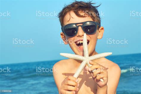 관광 시즌에 바다 해안 여름의 맑은 날에 하늘과 밝은 푸른 바다의 배경에 불가사리를 들고 행복 웃는 소년 여름 가족 휴가