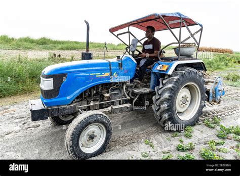 A Young Man Driving A Tractor In The Field A Male Driver Operating A