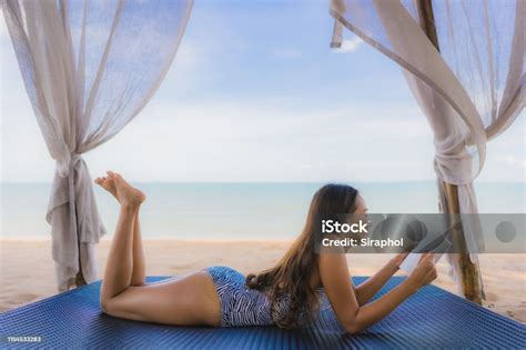 초상화 아름 다운 젊은 아시아 여자 독서 책 행복 한 미소와 휴식 라운지 침대의 자 해변 바다에서 레저 모래에 대한 스톡 사진 및 기타 이미지 Istock