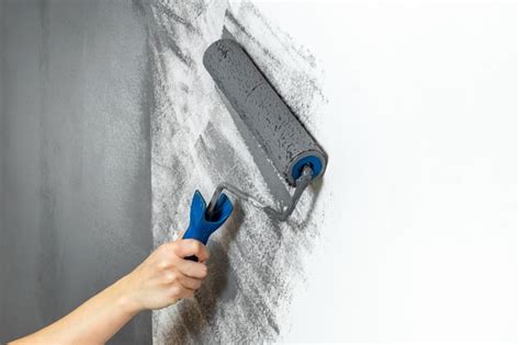 Premium Photo Female Hand Closeup Paints A Wall In Gray The Concept Of Repair Change Design