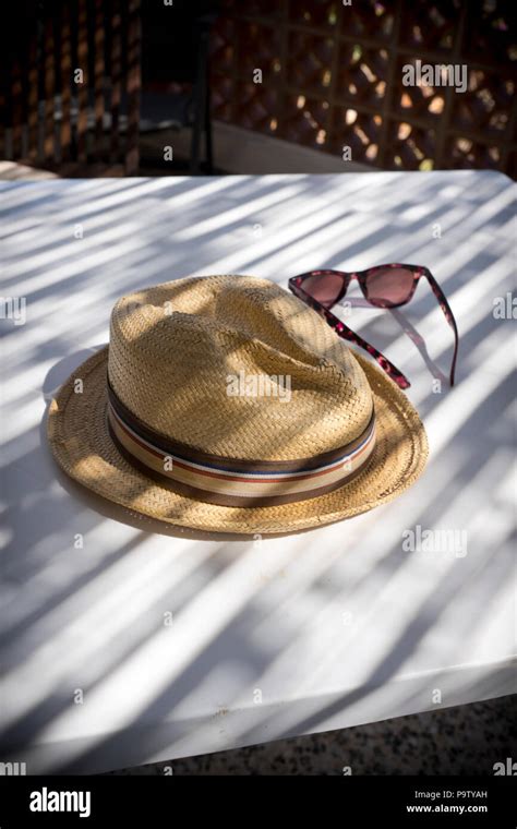 Still Life Of Well Used Mans Straw Hat With Stripey Band Next To Turtle Shell Patterned
