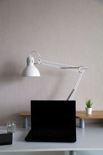 현대 작업 사무실의 내부 흰색 테이블에 작은 식물 물 한 잔과 검은 노트북 흰색 램프 데스크톱 조직 수직 방향 0명에 대한 스톡