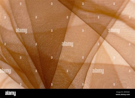 Translucent Fine Material In Beige Brown And Tan Forms Triangular Shapes The Fabric Is Backlit