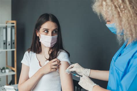 의료용 마스크를 착용한 백인 여성이 병원에서 백신 접종 캠페인 중 코로나19 예방 접종을 받고 있다 코로나 바이러스 또는 인플루엔자의 예방 코로나 바이러스와 독감 예방 주사