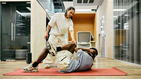 한 남자가 등 스트레칭을 하고 있고 다른 남자가 지켜보고 있다 사진 Unsplash의 사무실 이미지