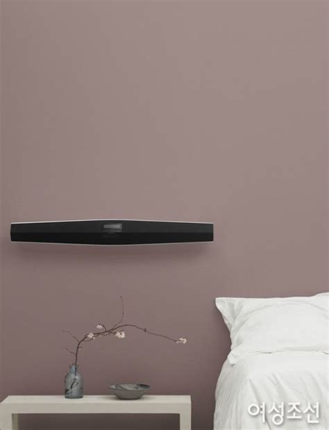 백색 베드와 보라색 벽 옆에 앉아있는 홈 인테리어 조명