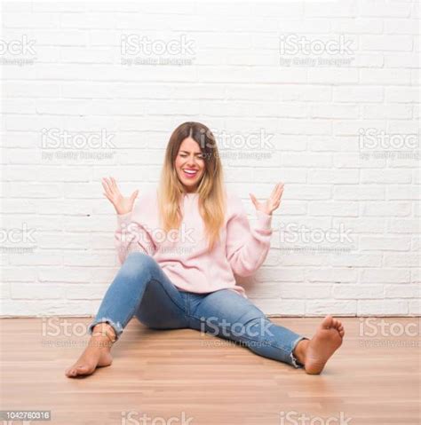 미친 미친 무기와 성공을 위한 축 하는 백색 벽돌 벽을 통해 바닥에 앉아 젊은 성인 여자 고 흥분 비명 눈을 폐쇄 우승자 개념 기이함에 대한 스톡 사진 및 기타 이미지