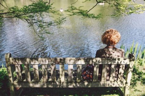 Premium Photo Rear View Of Woman Sitting On Wooden Bench Against Lake