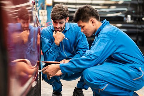 현대 자동차 서비스 상점에서 체크 리스트를 사용하여 자동차 타이어와 휠을 검사하는 두 명의 전문 적인 모습 기술자 자동차 비즈니스 또는 자동차 수리 개념 자동차 정비공에