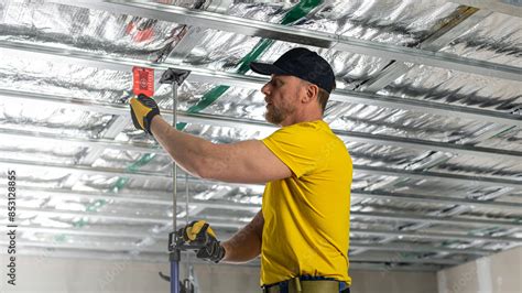 Plasterboard Worker Making A Plasterboard Ceiling He Is Adjusting The Correct Height Of Ceiling