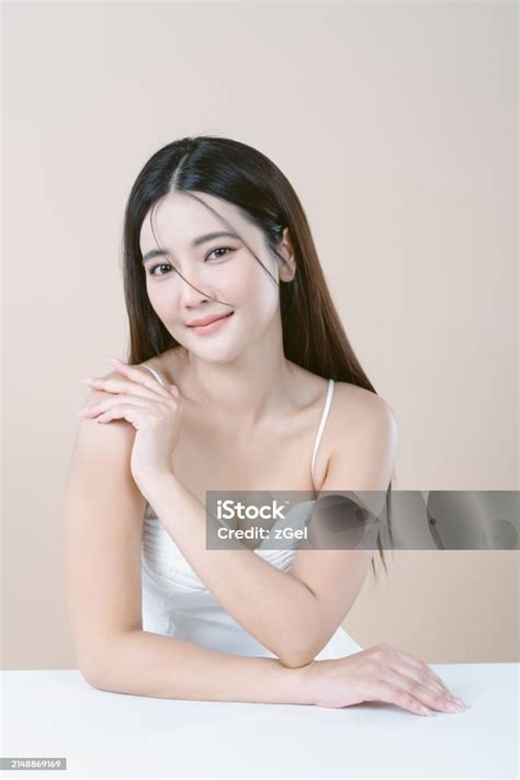 아름 다운 아시아 여자가 자연 화장을 하고 베이지 색 배경 위에 고립 된 곳을 바라 보고 있습니다 페이스 케어 페이셜 트리트먼트 뷰티 및 스파 스킨 케어 및 미용 개념