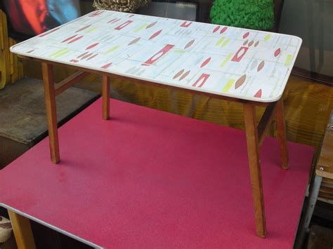 A White Table Sitting On Top Of A Pink Rug In Front Of A Tv Screen