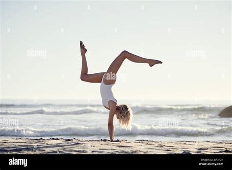 Life Is Just Simpler At The Beach Full Length Shot Of A Young Woman Doing A Handstand On The