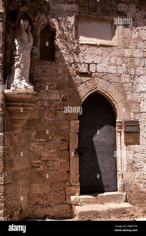The Facade Of A Medieval Chapel With An Arched Door And A Statue Of The