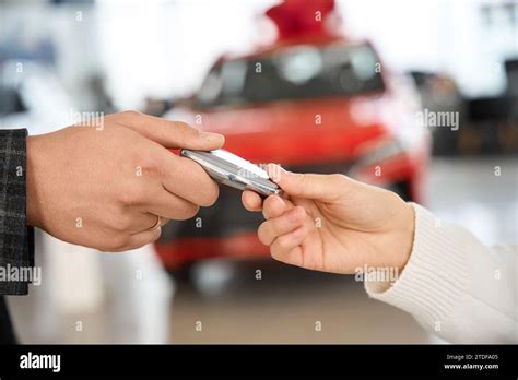 Salesman Giving Keys Of New Automobile To Woman Customer In Dealership