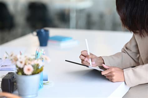 그녀의 워크 스테이션에서 디지털 태블릿에 스타일러스 펜 그리기 스타일러스 펜을 들고 여성 디자이너 손의 자른 샷 공란에 대한