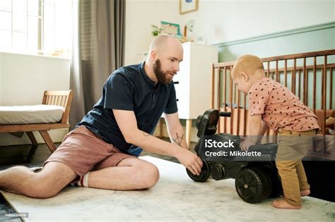 아버지 아이 그리고 재미 성장 및 발달을 위해 가족 가정 침실에서 장난감 자전거를 가지고 놀고 있습니다 유아 아이와 장난감을 가진 남자 또는 아빠는 바닥에서 함께 즐거운