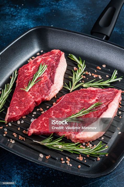 그릴 프라이팬에 생 엉덩이 또는 등심 쇠고기 고기 스테이크를 요리 할 준비가되었습니다 파란색 배경입니다 위쪽 보기 0명에 대한 스톡 사진 및 기타 이미지 Istock