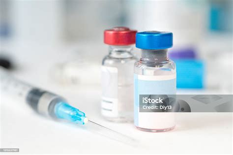 파란색 그라데이션 배경이있는 흰색 테이블에 주입을위한 빈 라벨 의료 유리 유리 및 플라스틱 주사기 예방 접종 당뇨병 및 미용 주사의 개념 공간을 복사합니다 당뇨병에 대한