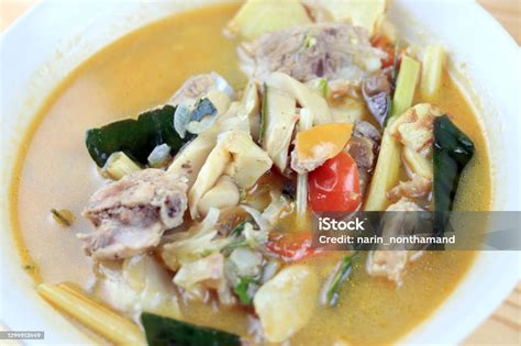 매운 삶은 돼지 고기 뼈와 짚 버섯 야생 토마토 나무 테이블에 흰색 그릇에 톰 얌 수프에 허브 태국 스타일의 음식에 톰 얌 수프 돼지 고기 건강한 생활방식에 대한 스톡 사진