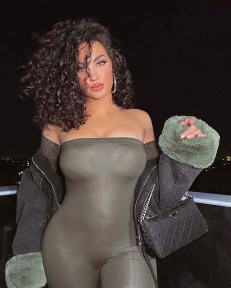 A Woman In Grey Bodysuit Posing For The Camera With Her Hand On Her Hip