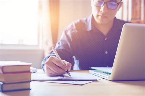 젊은 남성 학생은 대학 캠퍼스에서 강의를 준비 하는 동안 휴대용 그물 책에서 정보를 쓰고 카페에 앉아있는 동안 노트북 컴퓨터에서