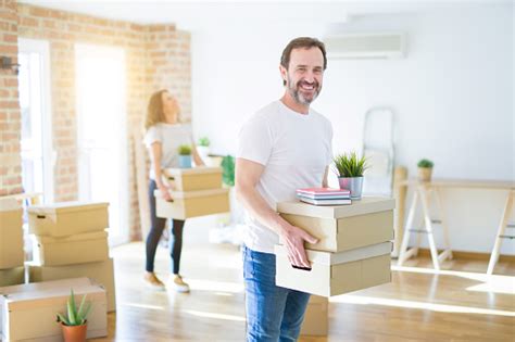 새 집으로 이사하는 중년 노인 부부 새 아파트와 사랑에 행복하게 웃고 골판지 상자를 들고 있는 남자 2명에 대한 스톡 사진 및