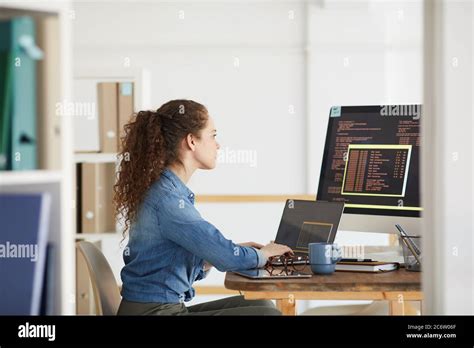 side view portrait of female it developer using computer while coding