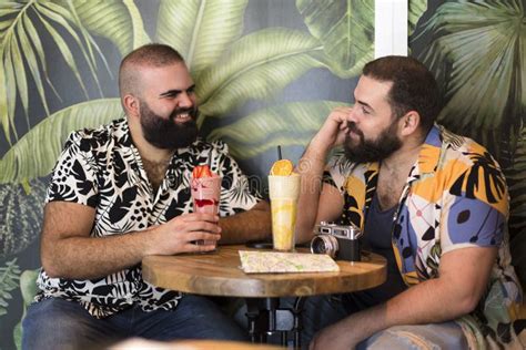 Young Gay Tourist Couple Having A Cocktail In A Tropical Beach Bar