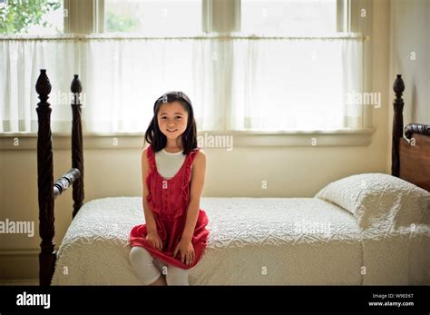 Young Girl Sits On The Edge Of A Bed And Smiles As She Poses For A