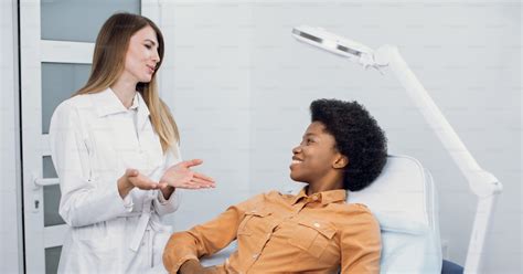 미용 클리닉에서의 상담 여성 전문 미용 의사가 예쁜 미소를 짓는 아프리카 여성 환자와 이야기하고 피부 관리 및 치료에 대한 좋은 소식을 전합니다 피부 관리 및 미용