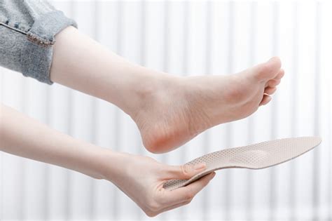 식탁에 앉아 있는 동안 깔창을 들고 있는 의사 정형 외과 의사는 의료 기기를 테스트합니다 정형 외과 깔창 발 관리 플랫 피트 보정 평평한 발 및 발 질환의 치료 및 예방