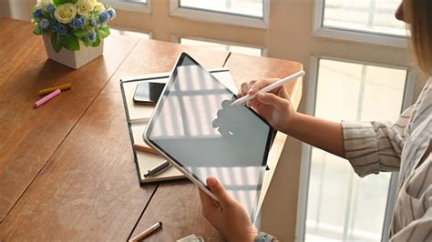 나무 테이블에 창조적 인 프로젝트와 그녀의 태블릿과 스타일러스 펜을 사용하는 여성의 그래픽 디자이너에 대한 스톡 사진 및 기타