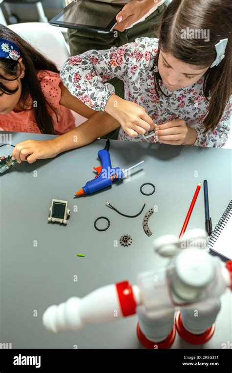 Student Assembling Machine Pieces Next To Her Teacher And To