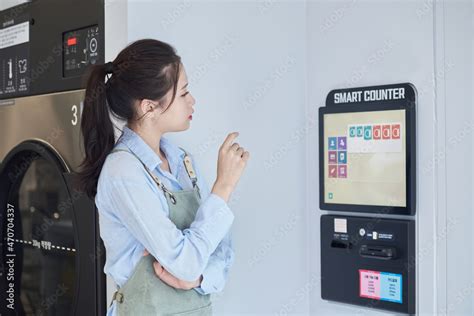 셀프 서비스 세탁실에서 빨래를 손에 올리고 키오스크를 작동중인 젊은 아시아 한국 여자 모델 Stock Foto Adobe Stock