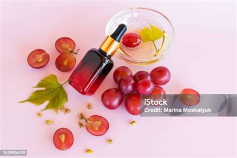 포도 기름 한 그릇이있는 분홍색 배경에 포도 씨앗의 자연 요법이있는 여러 가지 색상의 유리로 만든 피펫이있는 화장품 병 건강관리와 의술에 대한 스톡 사진 및 기타 이미지