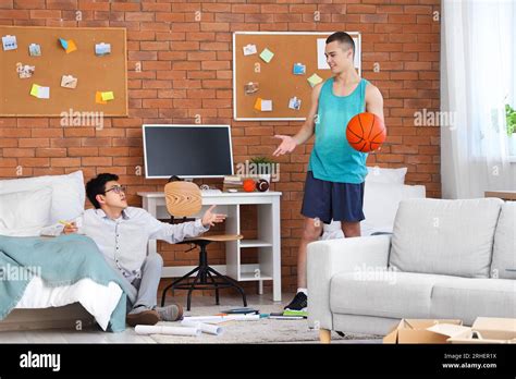 Sporty Teenage Boy With Ball And His Classmate Studying In Dorm Room Stock Photo Alamy