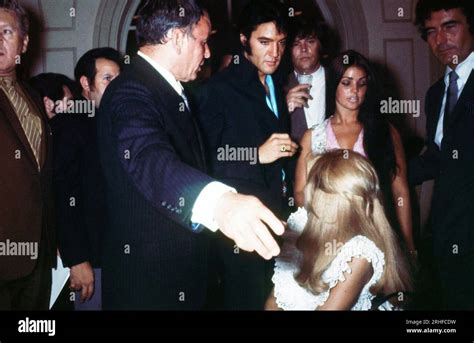 Elvis Presley Wearing Black Jacket Walking Through A Crowd With Wife