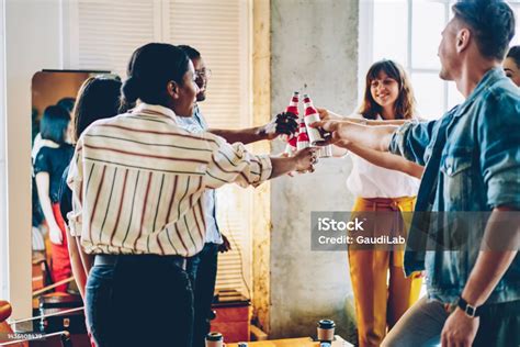 캐주얼 한 옷을 입은 다문화 젊은이들은 현대 아파트에서 알코홀 파티를 즐기는 편안하고 행복한 다양한 힙스터 남자모임에서 환호제스처를 연출합니다 20 24세에 대한 스톡 사진