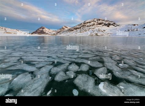 The Frozen Surface Of Lago Bianco Framed By Snowy Peaks Bernina Pass